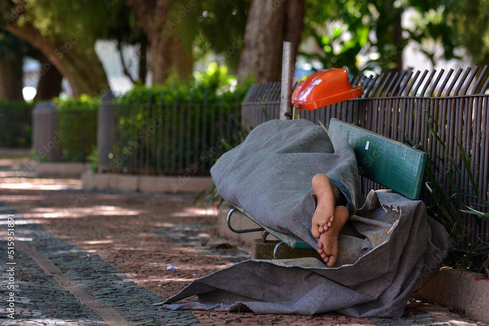 Homeless covered with blanket sleeping on a bench at Matriz Square ...