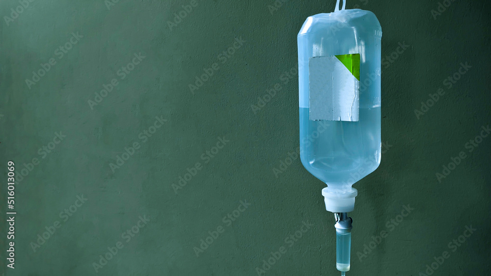 Medical Saline solution bottle container hanging on green background ...