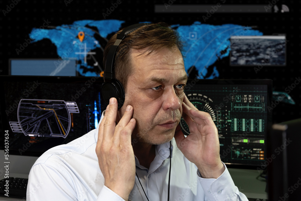 A secret agent wearing headphones watches the monitors and monitors in ...