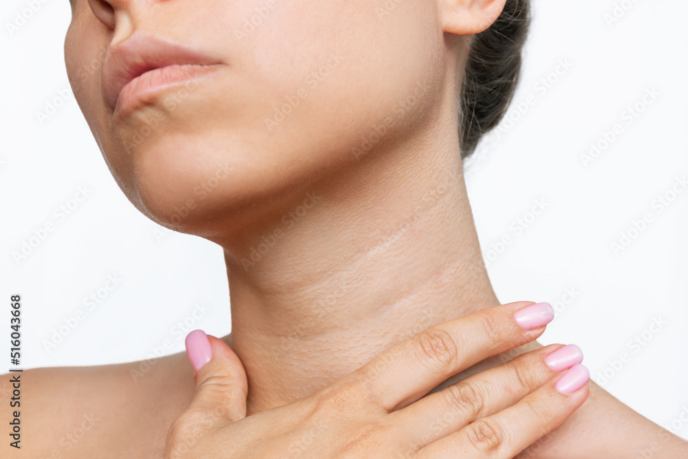 Cropped shot of a young woman touching her neck with her hand isolated ...
