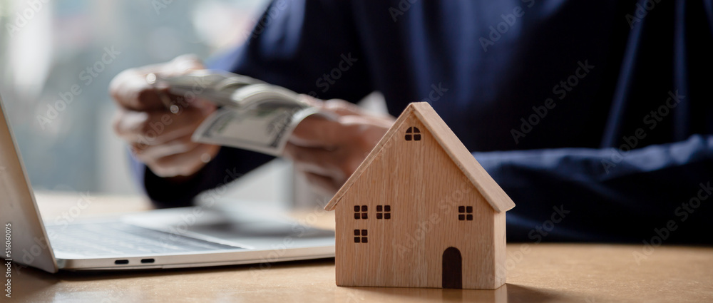 Men holding house model in hand and calculating financial chart for ...