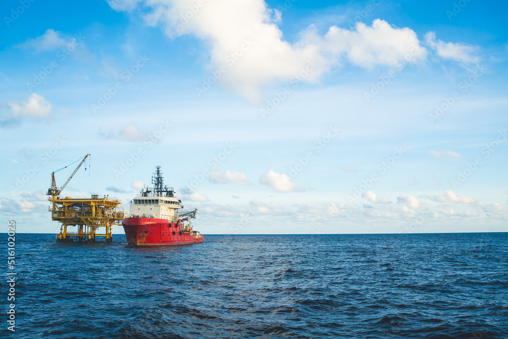 A tugboat anchors near an oil rig at an oil well to transport necessary ...