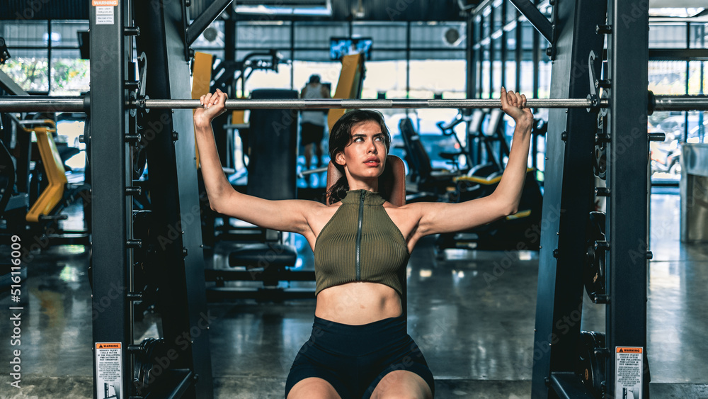 Young atheletic woman is working out in the gym. She looks focus and ...