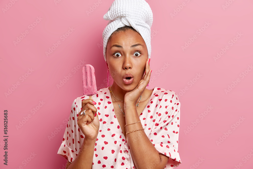 Surprised woman stares impressed at camera holds delicious ice cream on ...
