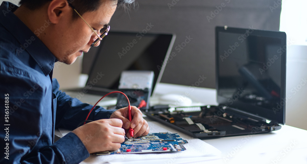 young man who is a computer technician A laptop motherboard repairman ...