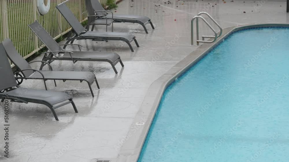 Rain drops falling on water surface of blue swimming pool, rainy day in ...
