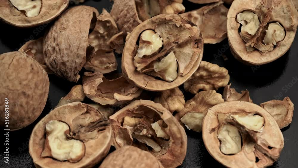 Lot of walnuts in the shell are spinning on a black background. Nuts ...