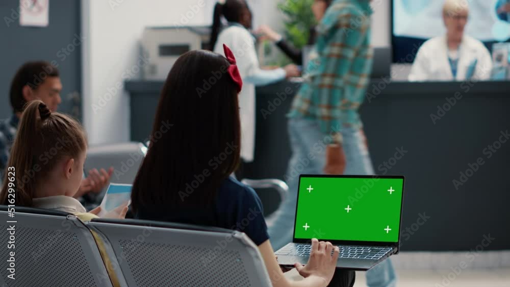 Mother and little girl using laptop with greenscreen in waiting room ...