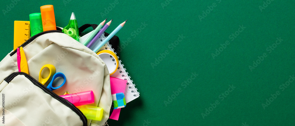 Backpack with colorful school supplies on green background. Back to ...