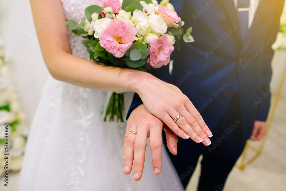 The bride and groom show off their precious gold wedding rings. Bouquet ...
