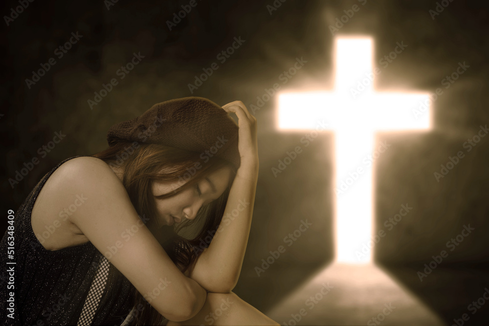 Sad woman sitting alone near a bright cross symbol Stock Photo | Adobe ...