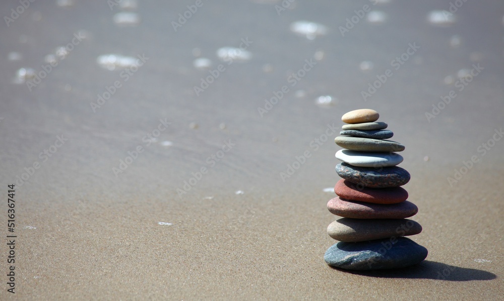 Vertical shot of stacked pebbles on the beach representing peace with ...