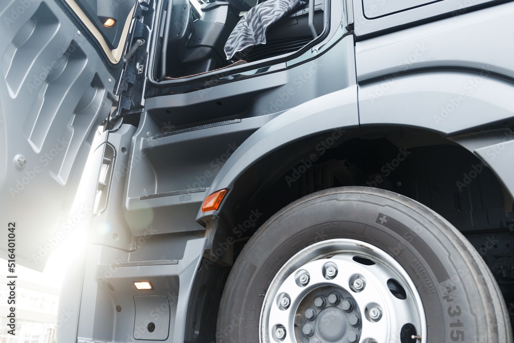 Bottom-up view of the open door of the truck cab. Bright sun in the gap ...