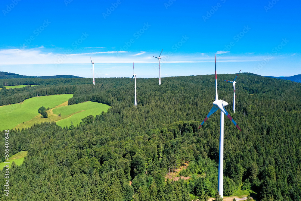 Aerial view of wind power plant in the bright green meadow and fir ...