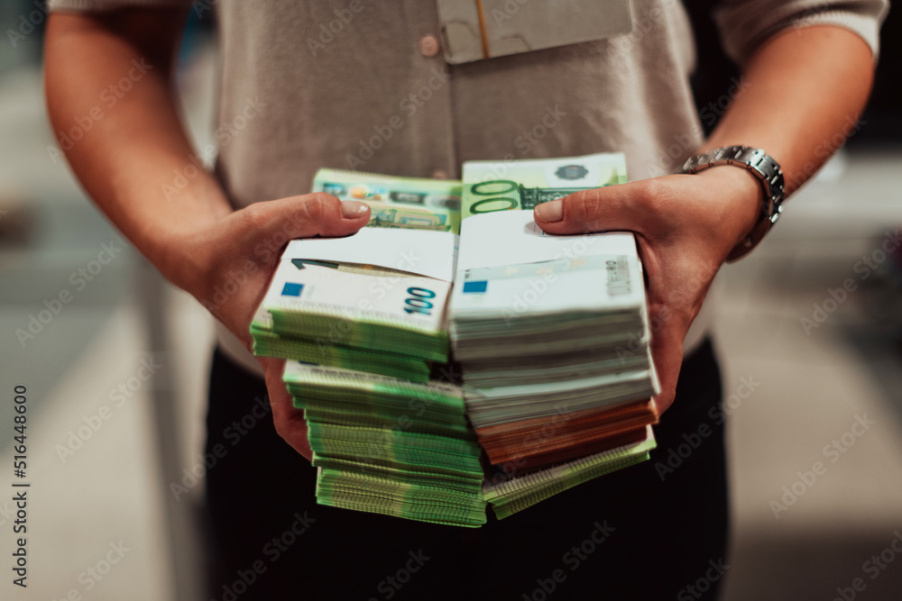 Bank employees holding a pile of paper banknotes while sorting and ...