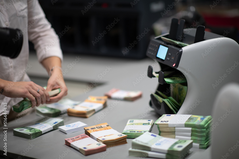 Bank employees using money counting machine while sorting and counting ...