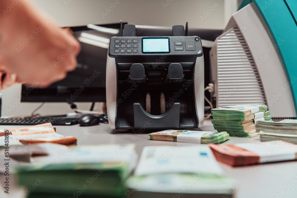 Bank employees using money counting machine while sorting and counting ...