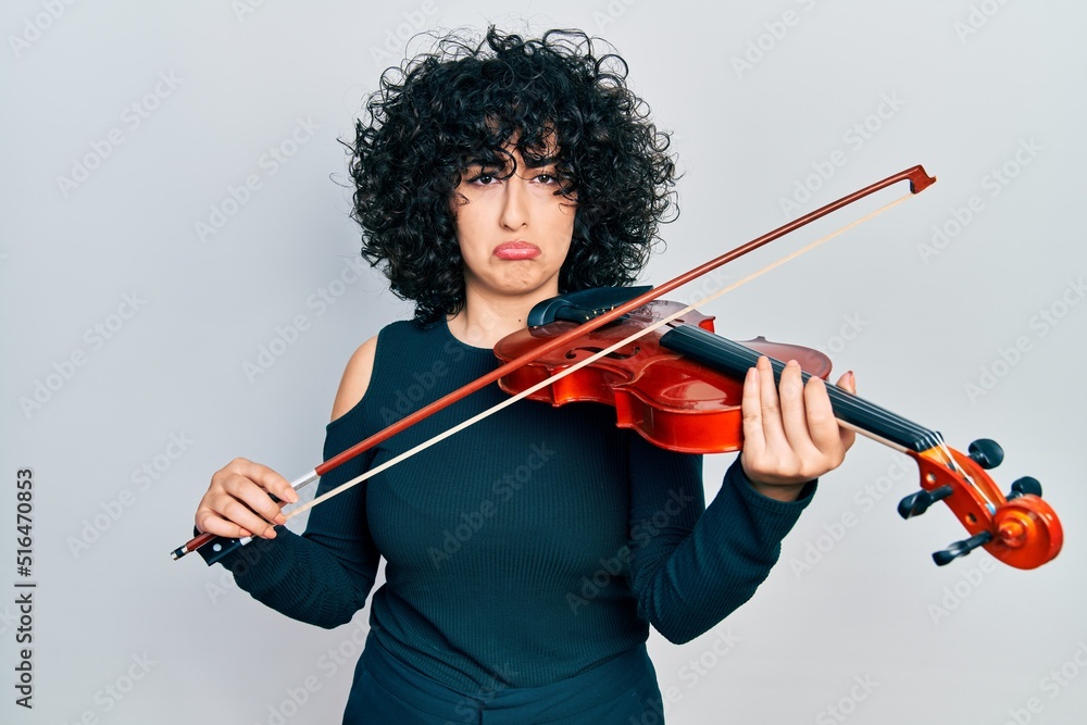Young middle east woman playing violin depressed and worry for distress ...