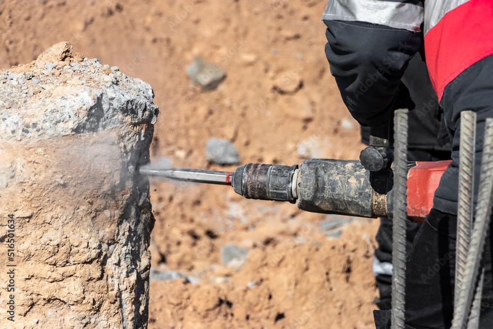A worker with a jackhammer breaks concrete piles. Felling the pile head ...