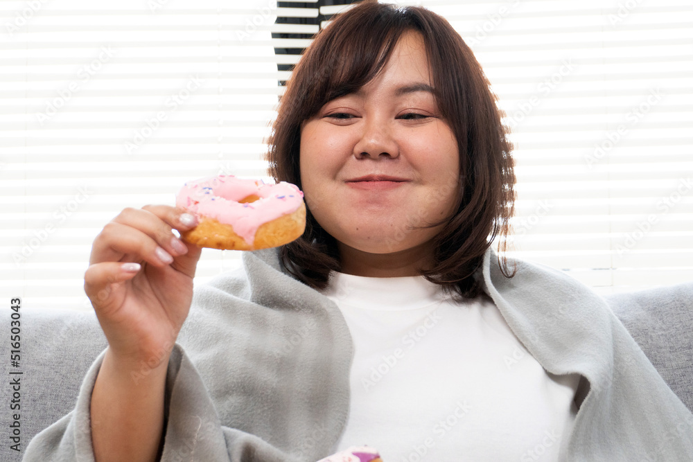Foto de Chubby Asian woman shows off her happiness when she eats a Donut. and potato snacks do ...