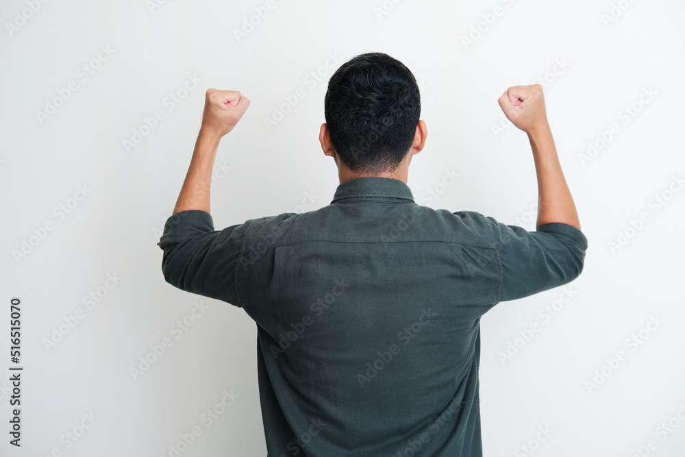 Back view of a man clenched both fist in the air showing winning ...