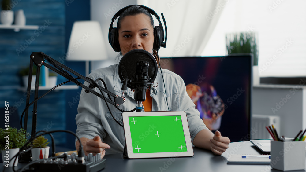 Influencer in studio promoting product on tablet with green screen ...