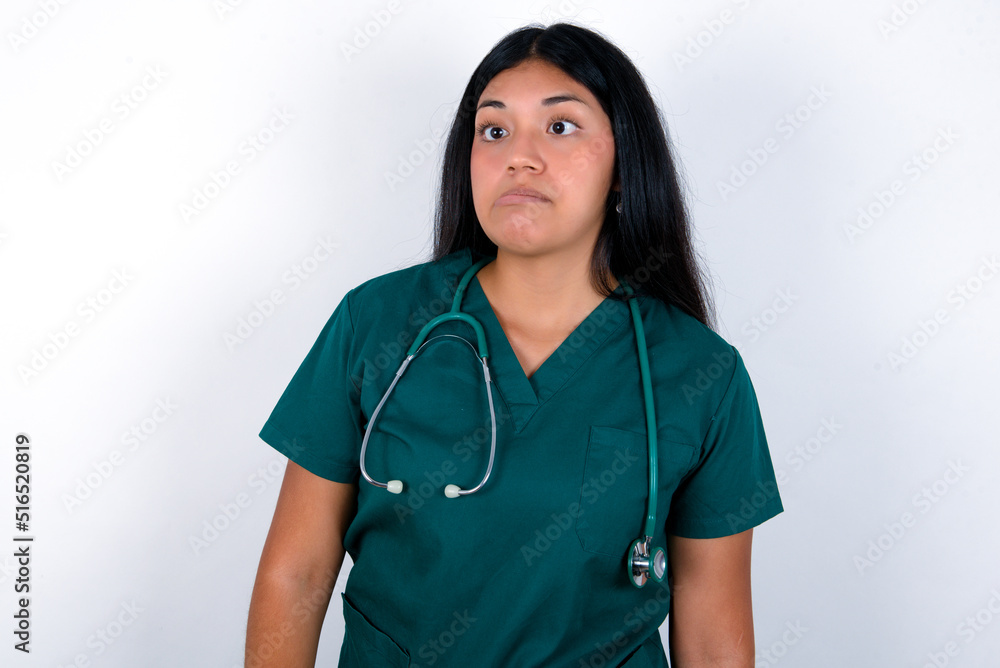 Doctor hispanic woman wearing surgeon uniform over white wall making ...