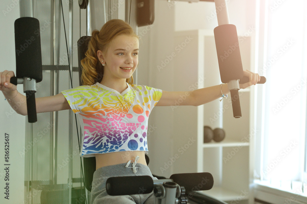 Beautiful teen girl is exercising in the gym Stock Photo | Adobe Stock