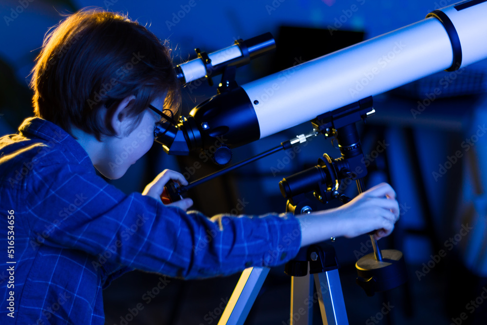 Boy carefully looks through a telescope. Smart inquisitive child ...