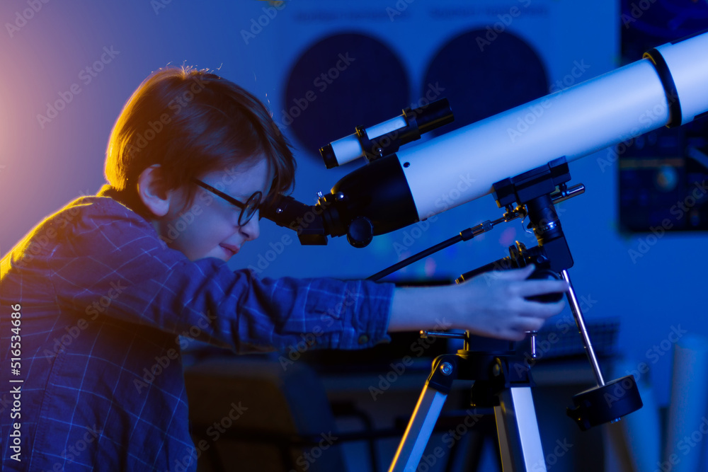 Boy carefully looks through a telescope. Smart inquisitive child ...
