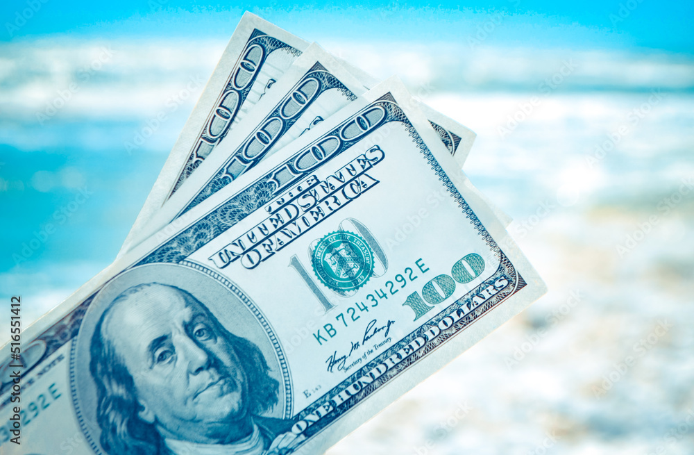 Girl holding money bill of 300 dollars on background of sea ocean waves ...