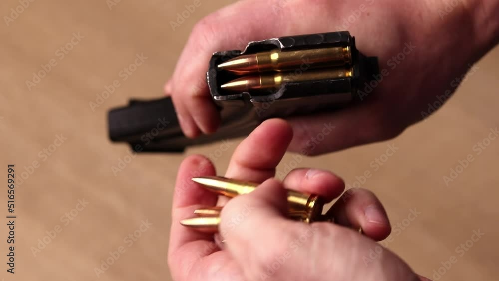 Male hands loading Kalashnikov assault rifle magazine with cartridges ...