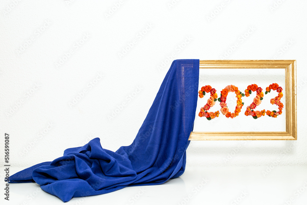 blue fabric uncovering a golden frame with 2023 written with orange ...