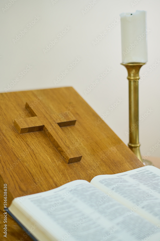 Part of pulpit with cross, burning candle and open Gospel with verses ...