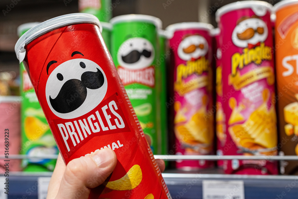 A buyer buys Pringles chips at a supermarket. Hand hold a new tube of ...