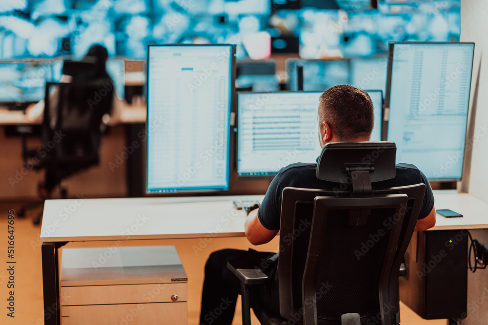 Male security operator working in a data system control room offices ...