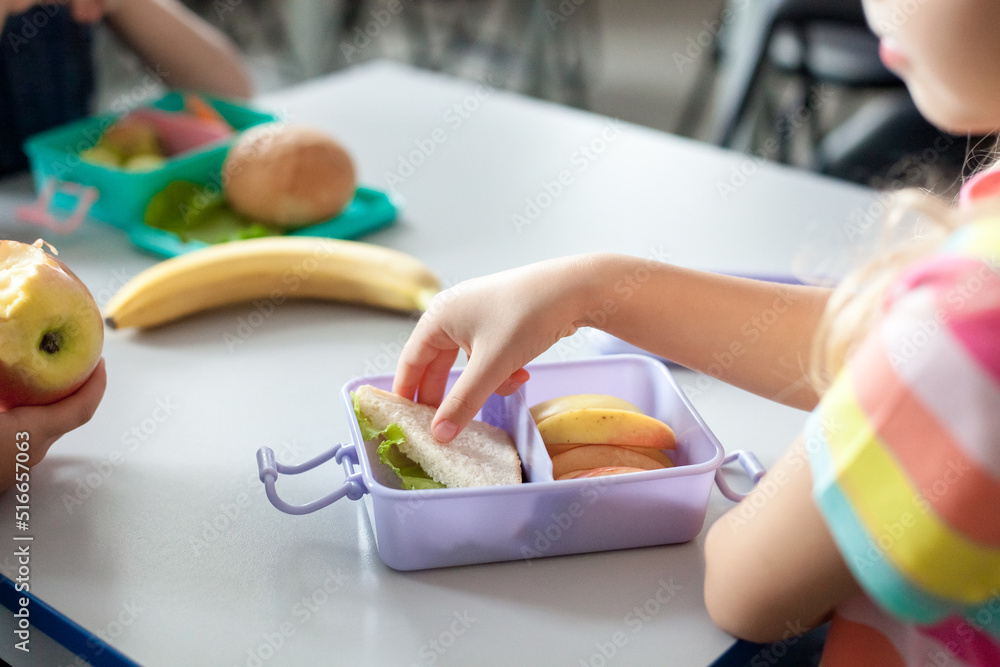 School children eating healthy food from packed lunch boxes. Kids at ...