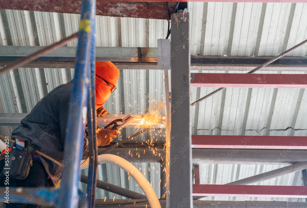Technician welding at height under roof for ceiling support. Stock ...