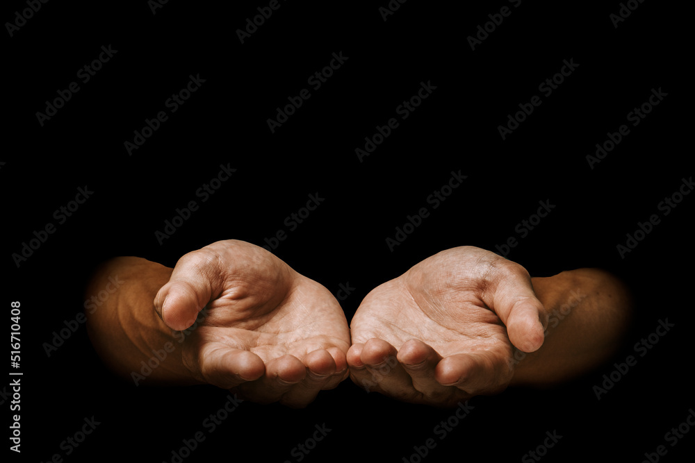 Praying hand with shadows reaching out against a dark background ...