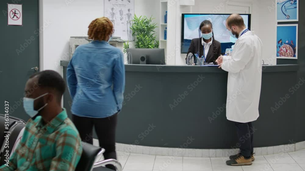 Doctor and receptionist talking about appointment at hospital reception ...