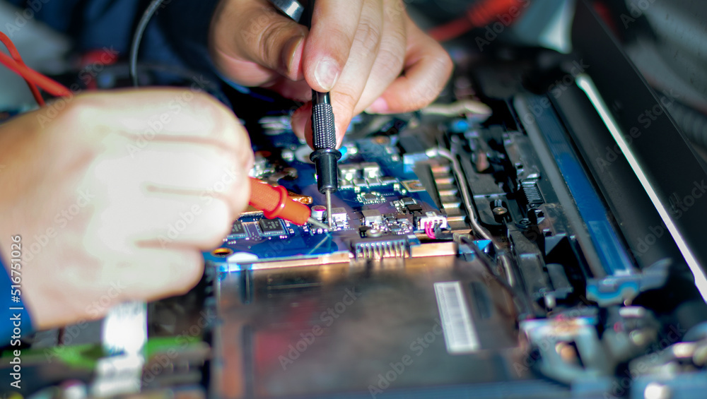 computer technician technician A laptop motherboard repairman is using an IC meter to look for ...