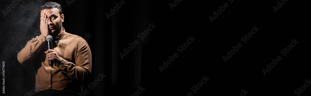 indian comedian covering eye and performing stand up comedy with ...