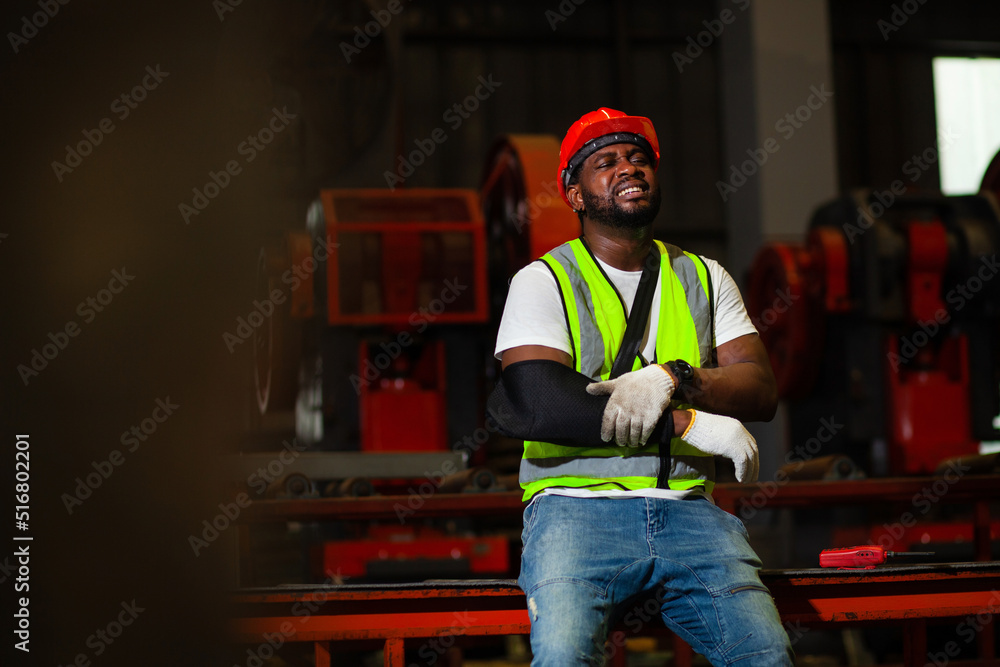 Foto de An African-American male worker who sits in a factory with his ...