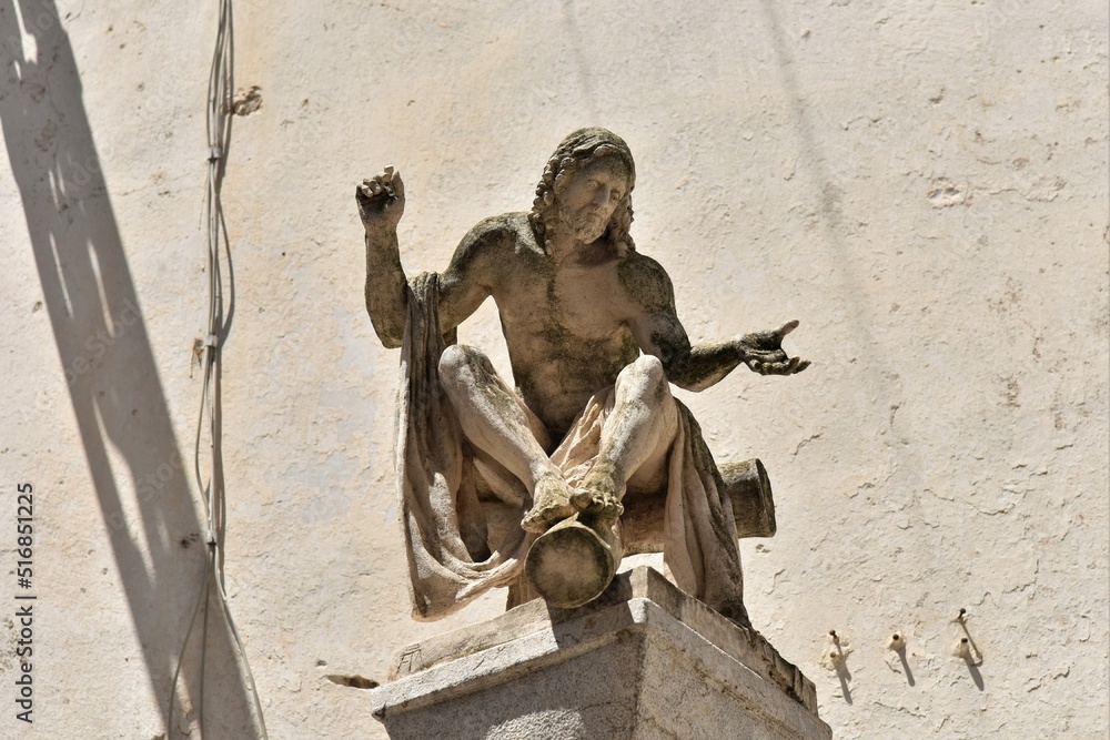 Unusual grey stone street statue of sitting Jesus with sweeping gesture ...
