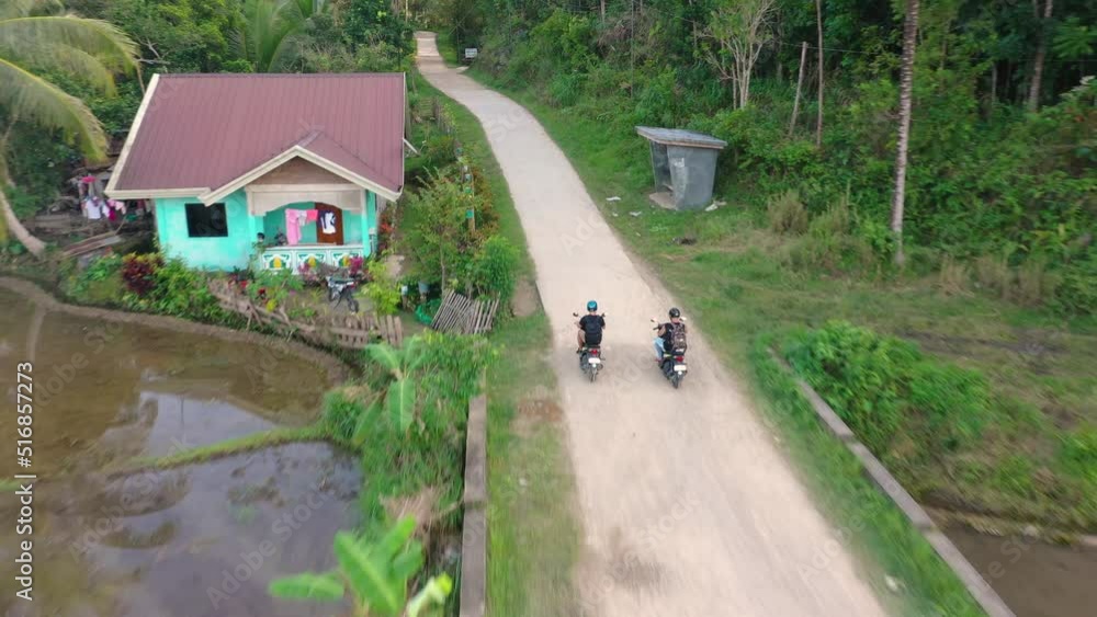 Drone footage following two mopeds driving on a country road in small ...