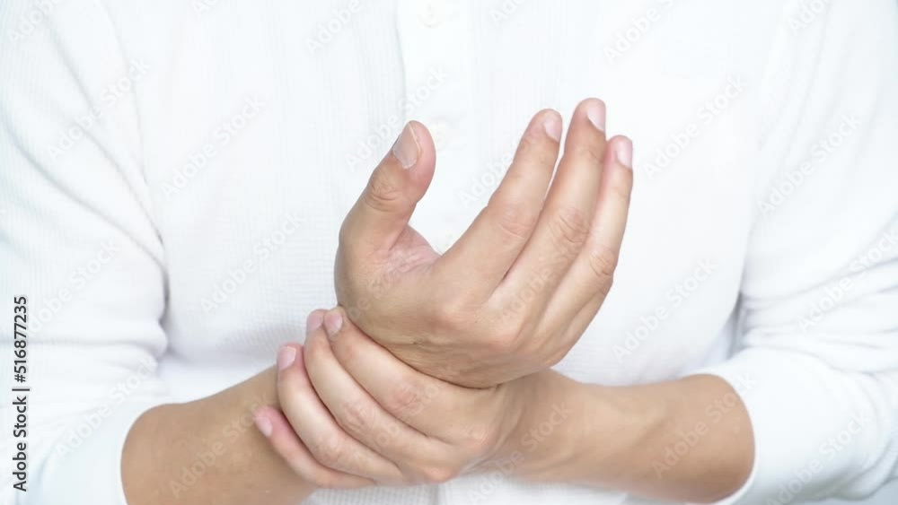 The man touches the wrist and thumb. He squeezes the knuckle of the ...