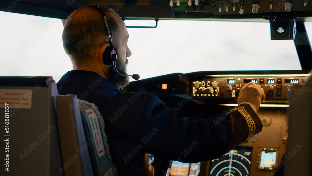 Airplane captain pushing buttons to fix altitude and longitude, flying ...