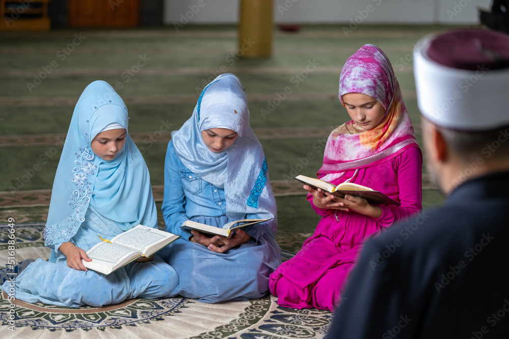 A Muslim teacher during the class teaching child girl to reading a holy ...