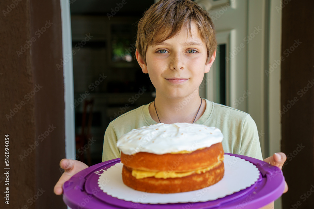 Happy blond preteen kid boy holding birthday cake, baked for mother or ...