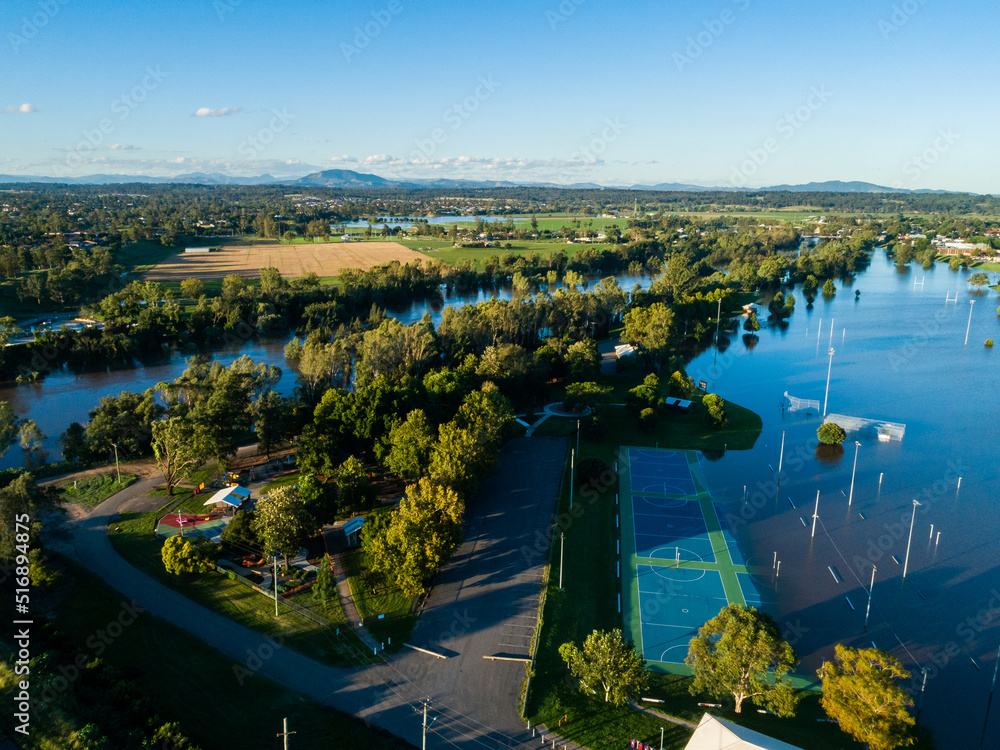 Flooded netball courts and park beside overflowing river with water ...